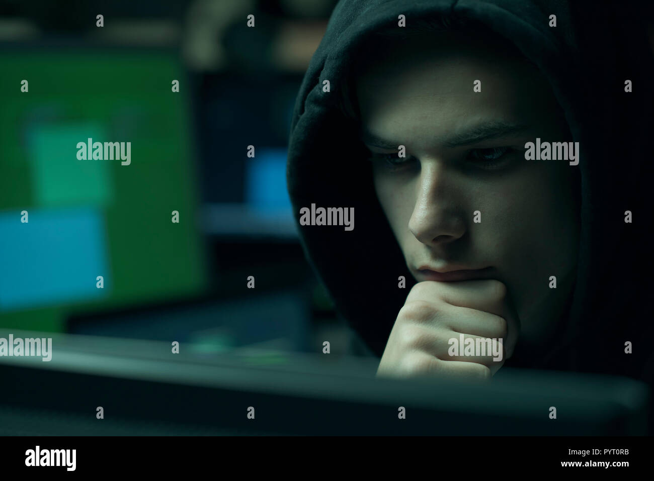 Cool young hacker with hoodie working with computers, cybercrime and ...