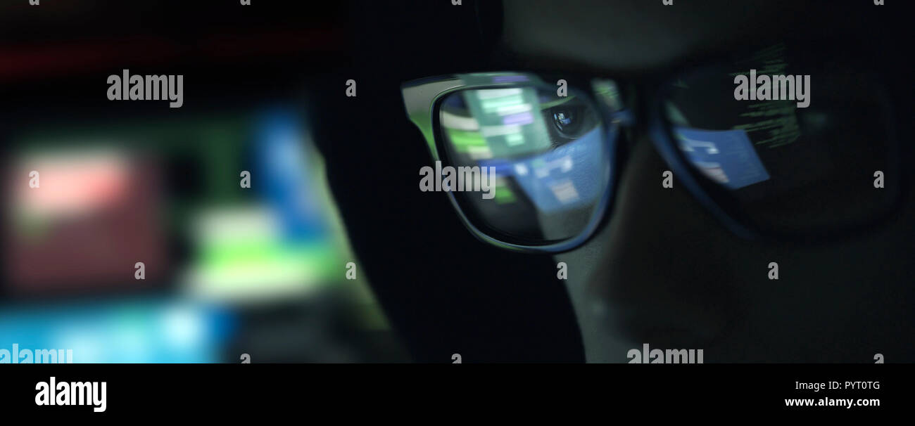 Nerd hacker with glasses working with a computer in the dark ...