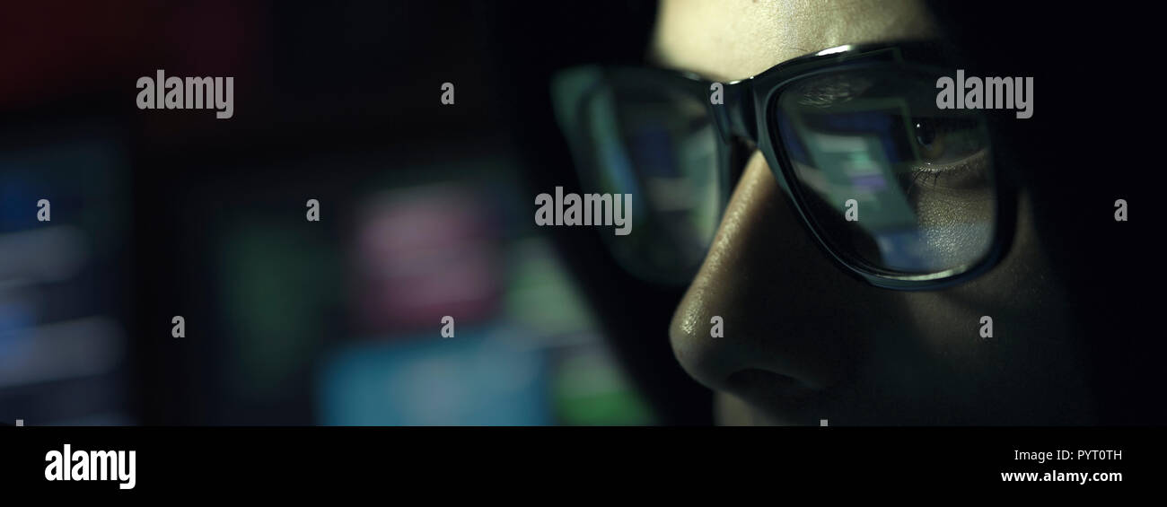 Nerd hacker with glasses working with a computer in the dark ...