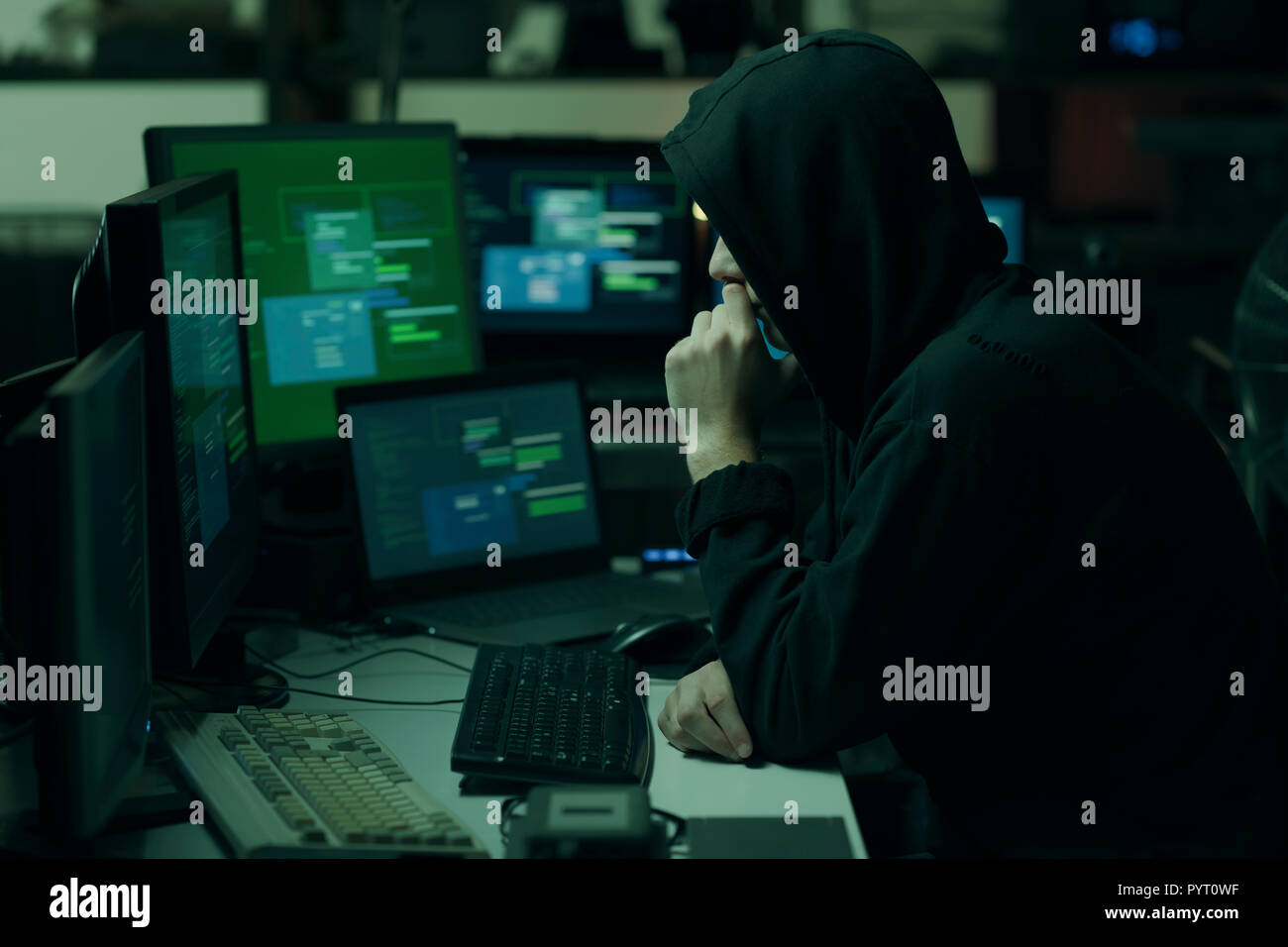 Young hacker with a hoodie thinking with hand on chin and working with ...