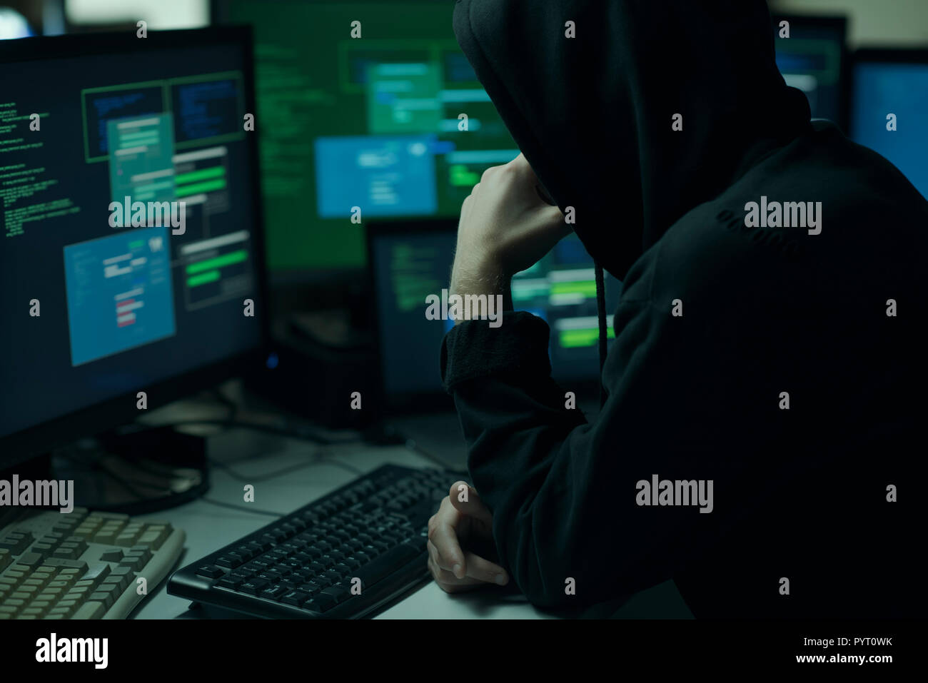 Young hacker with a hoodie thinking with hand on chin and working with ...