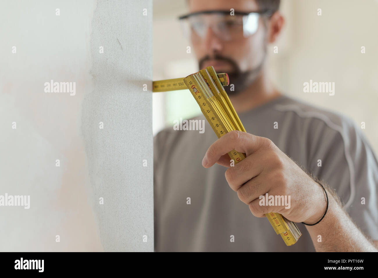 Man measuring a wall using a folding ruler: home renovation and ...