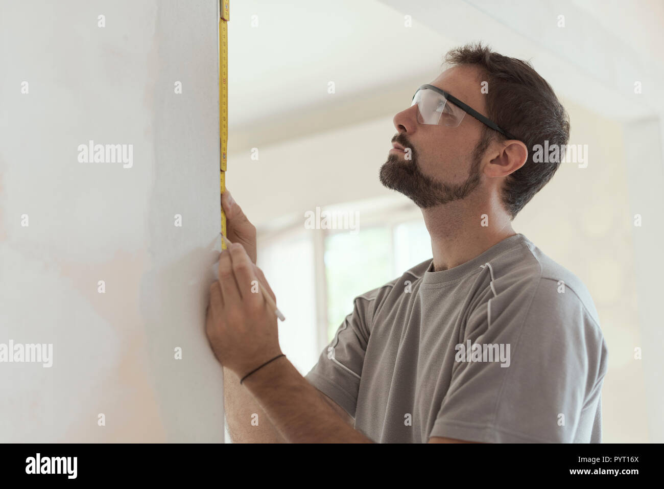 Man measuring a wall using a folding ruler: home renovation and ...
