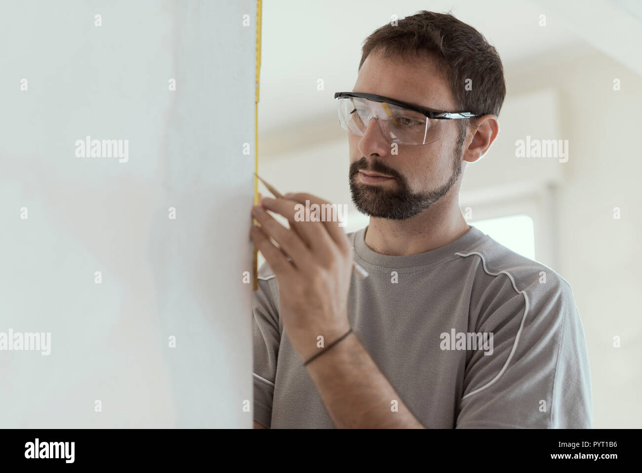 Man measuring a wall using a folding ruler: home renovation and ...