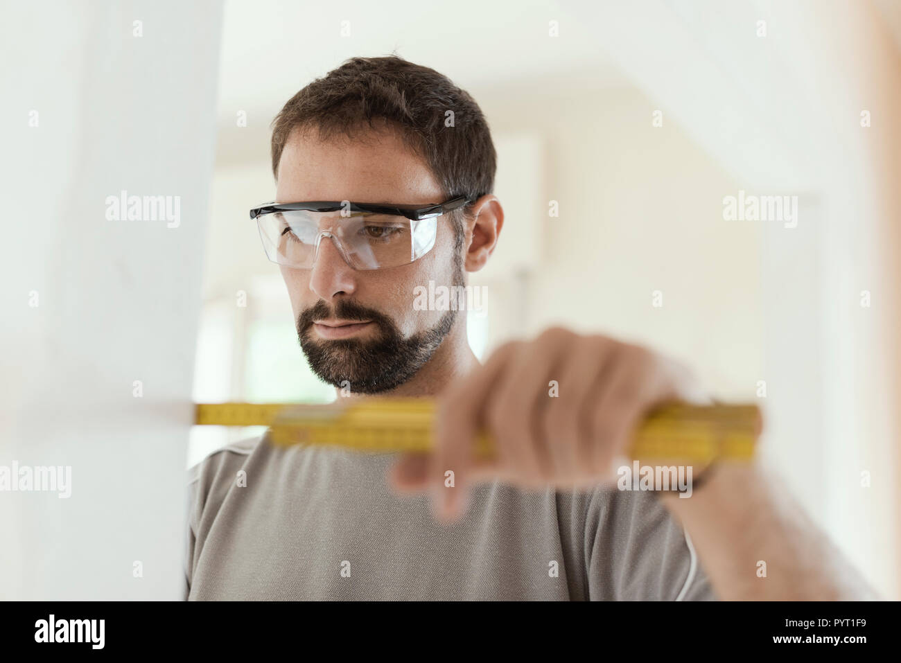 Man measuring a wall using a folding ruler: home renovation and ...