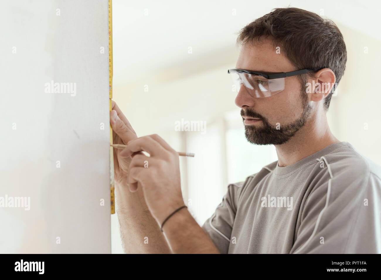 Man measuring a wall using a folding ruler: home renovation and ...