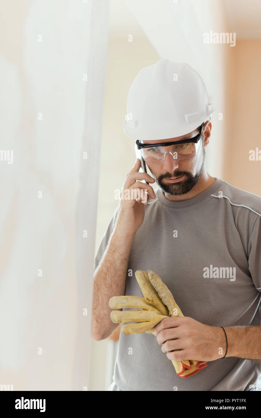 Professional builder with safety helmet having a phone call, home ...