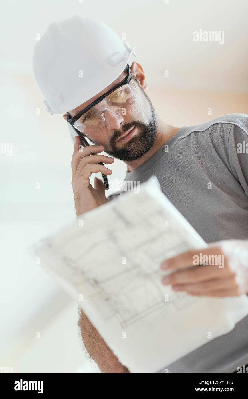 Professional construction worker checking a house project and calling ...
