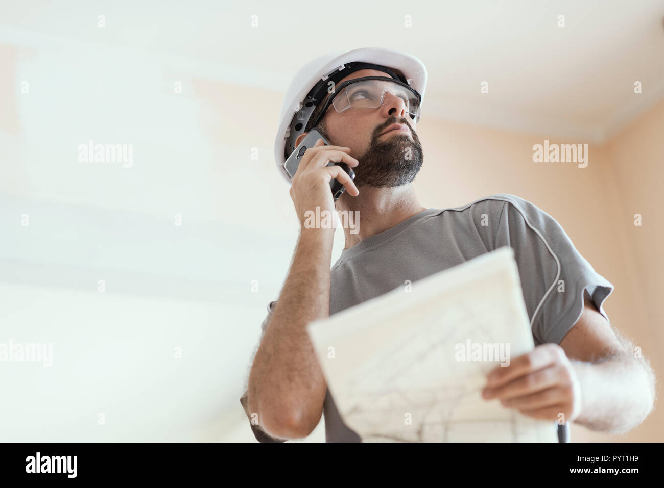 Professional construction worker checking a house project and calling ...