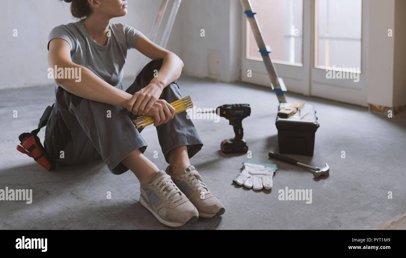 Woman sitting on the floor with tools and holding a folding ruler, she ...