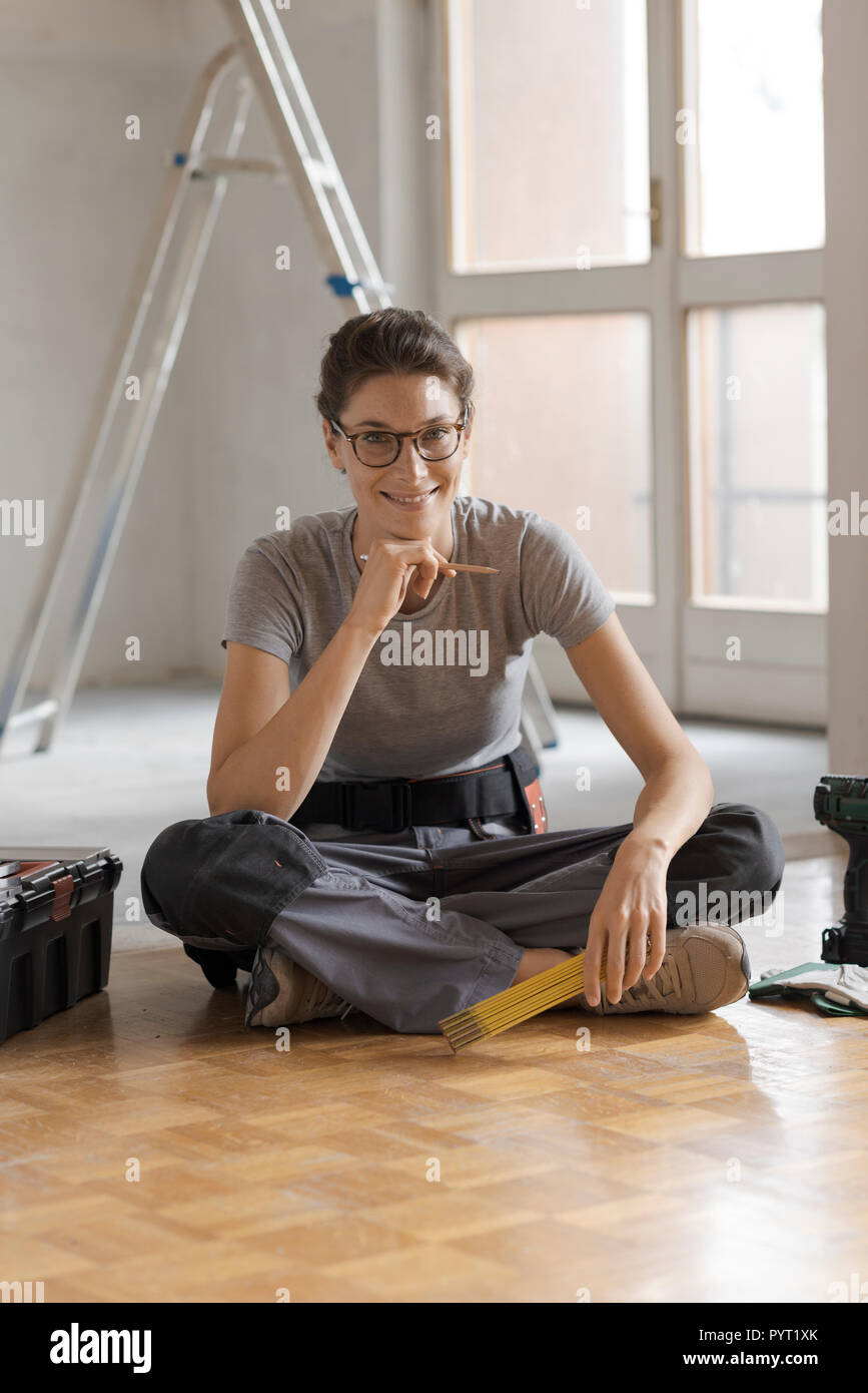 Attractive smiling woman working on a home renovation, she is sitting ...