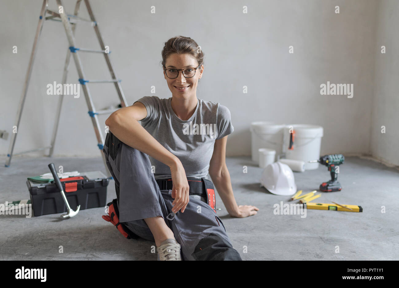 Attractive smiling woman renovating her house, she is sitting on the ...