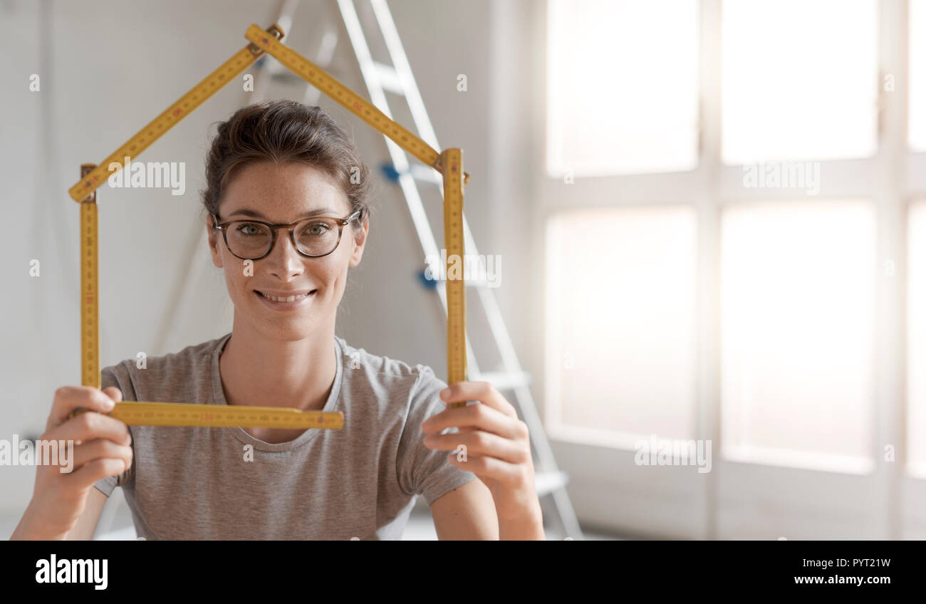 Woman making a house shape with a folding ruler and smiling, home ...