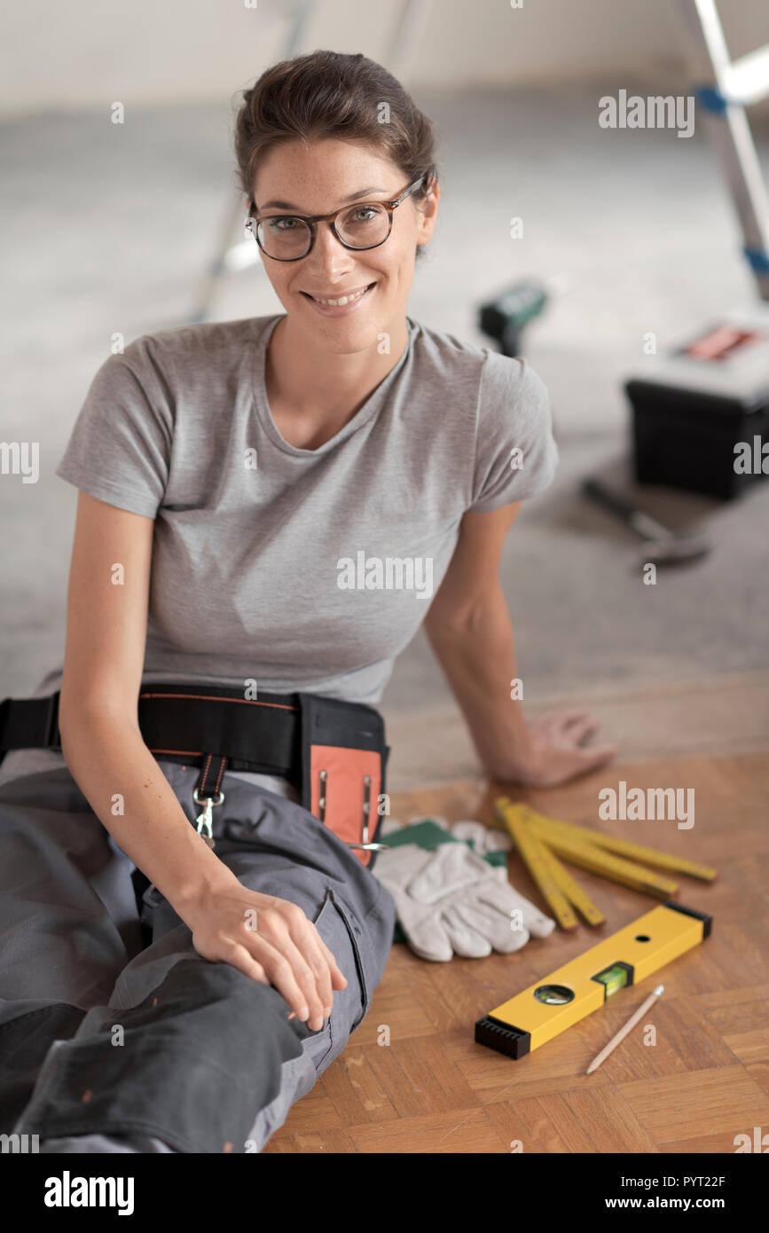 Attractive smiling woman renovating her house, she is sitting on the ...