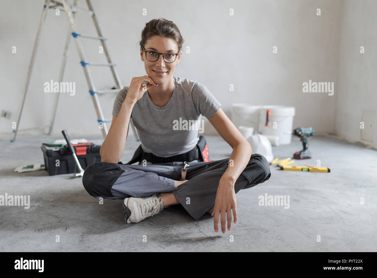 Attractive smiling woman renovating her house, she is sitting on the ...