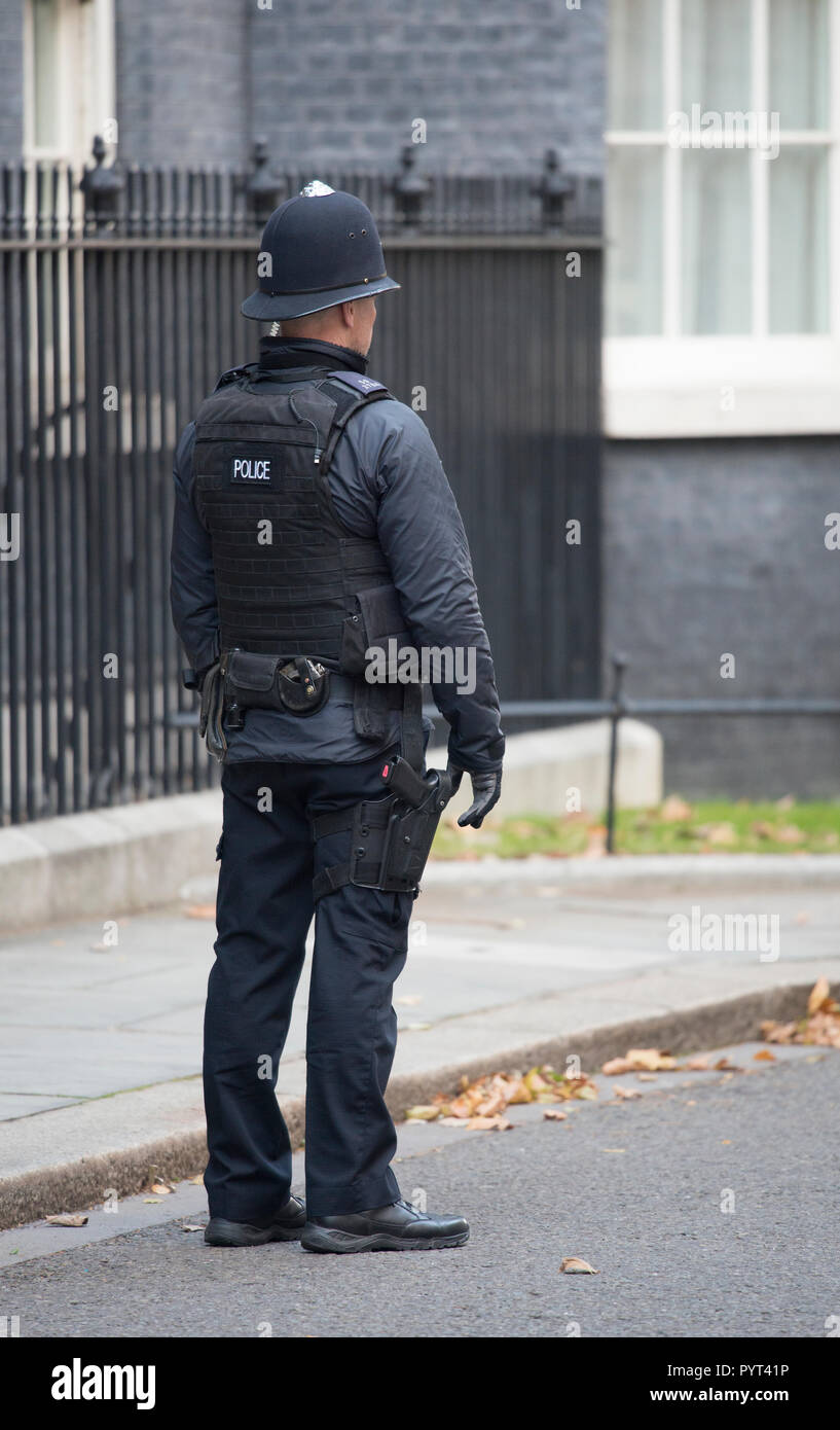 Armed uniformed police officer on guard outside 10 Downing Street with ...