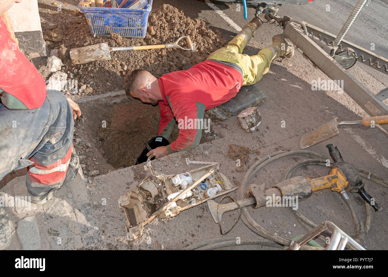 Installing a new water meter in the road. UK. Worker working face down ...