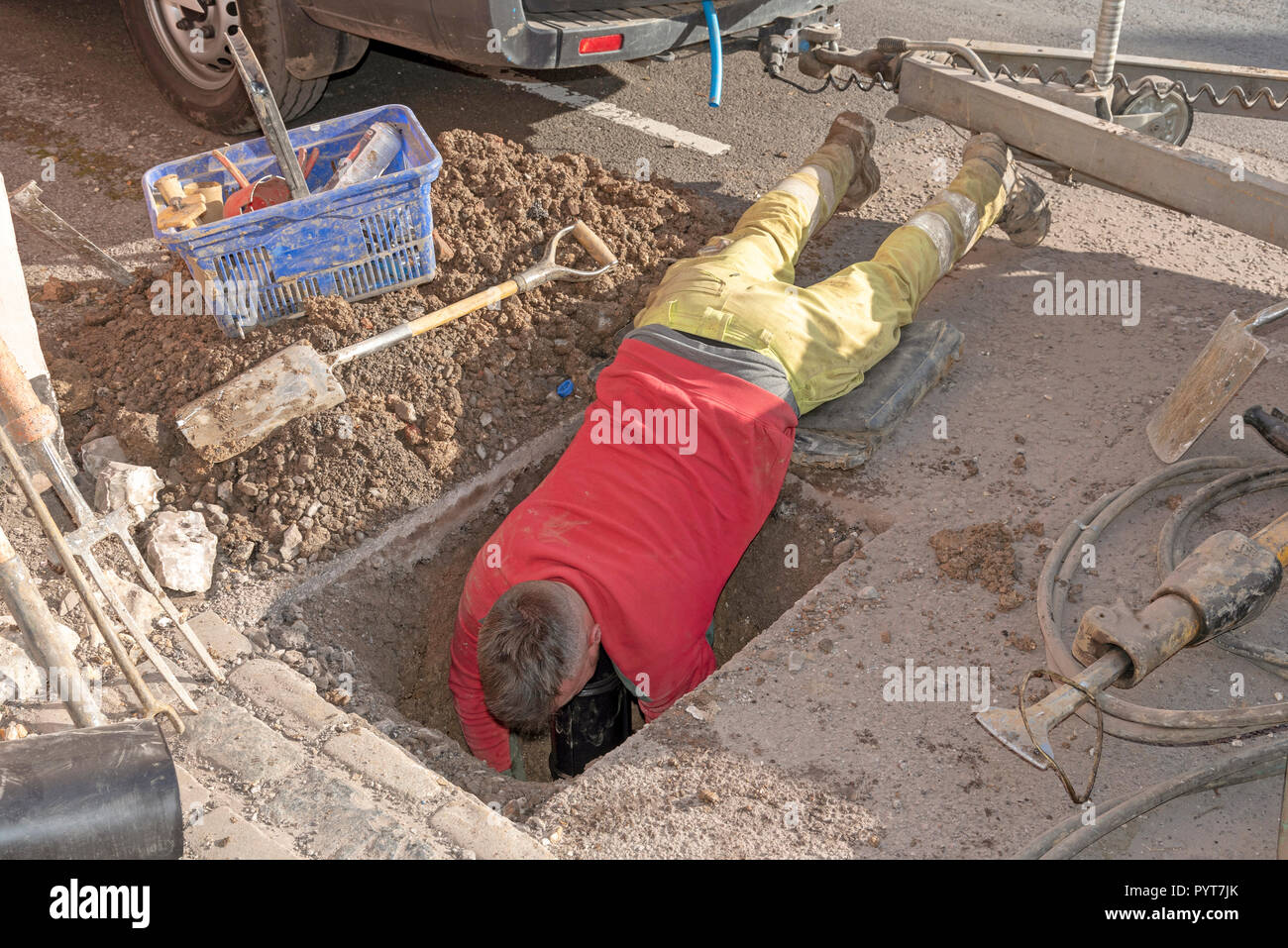 Installing a new water meter in the road. UK. Worker working face down ...