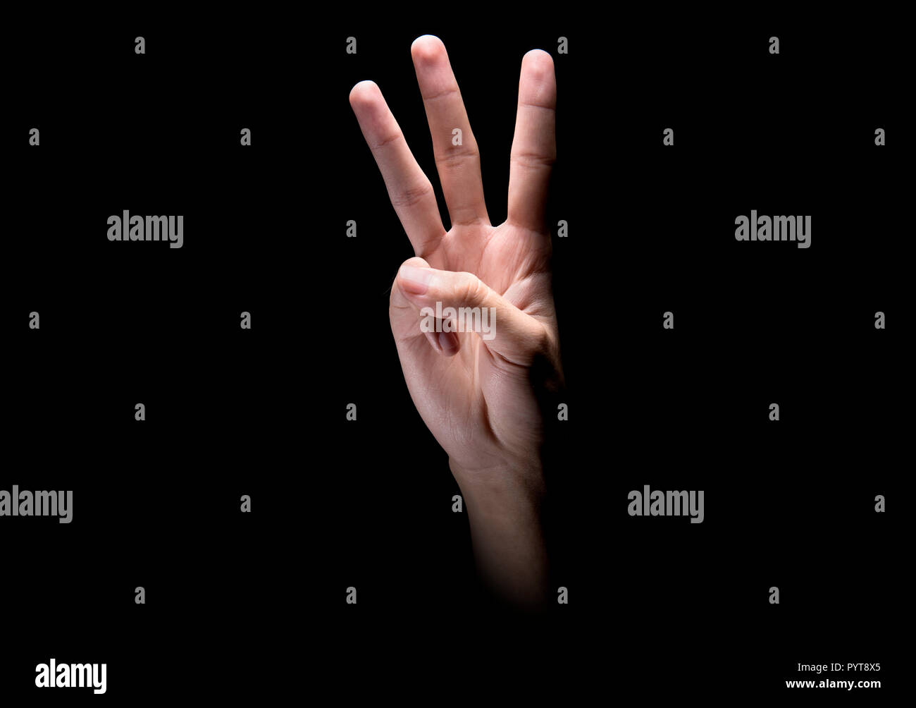 Male hands with three finger sign over dark background Stock Photo - Alamy