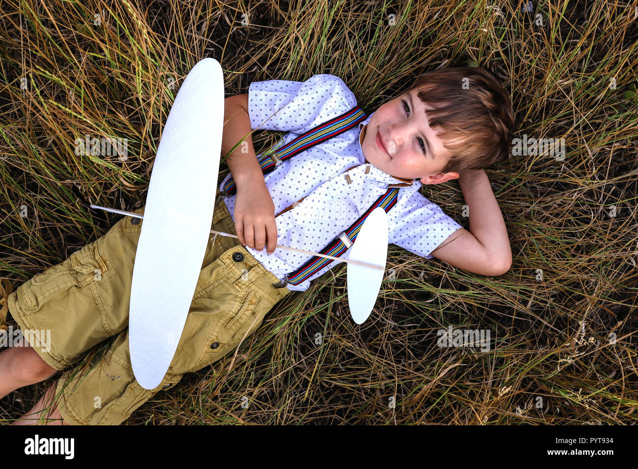 Happy boy lay in grass with plane Stock Photo - Alamy