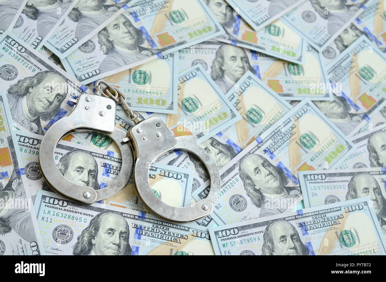 Silver police handcuffs lies on a many dollar bills Stock Photo - Alamy