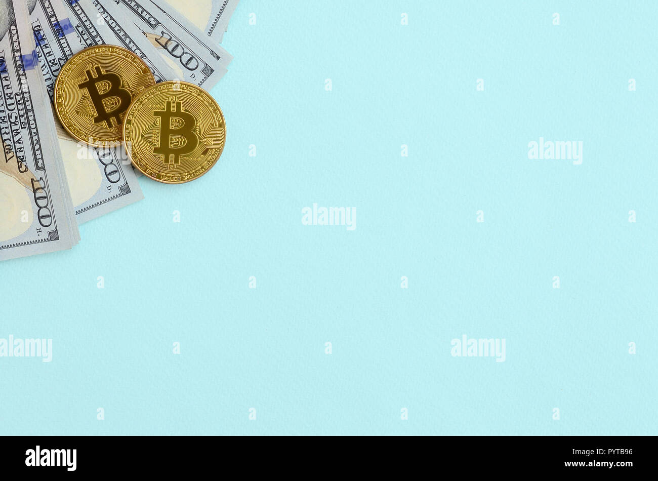 Golden bitcoins and hundred dollar bills lies on light blue background ...