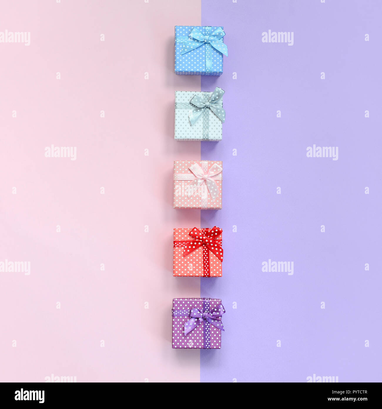 Small gift boxes of different colors with ribbons lies on a violet and ...