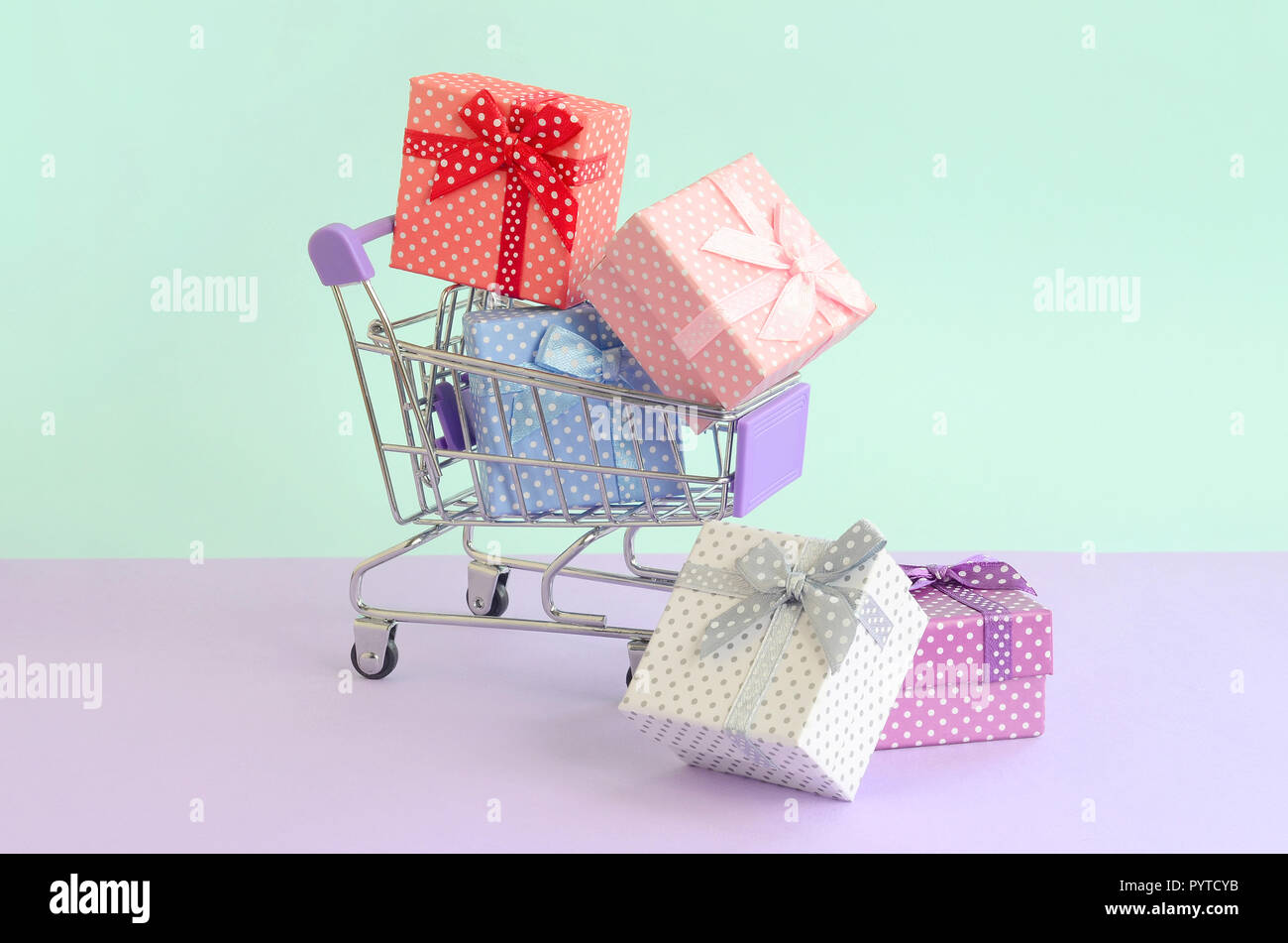 Small gift boxes of different colors with ribbons lies in shopping cart ...