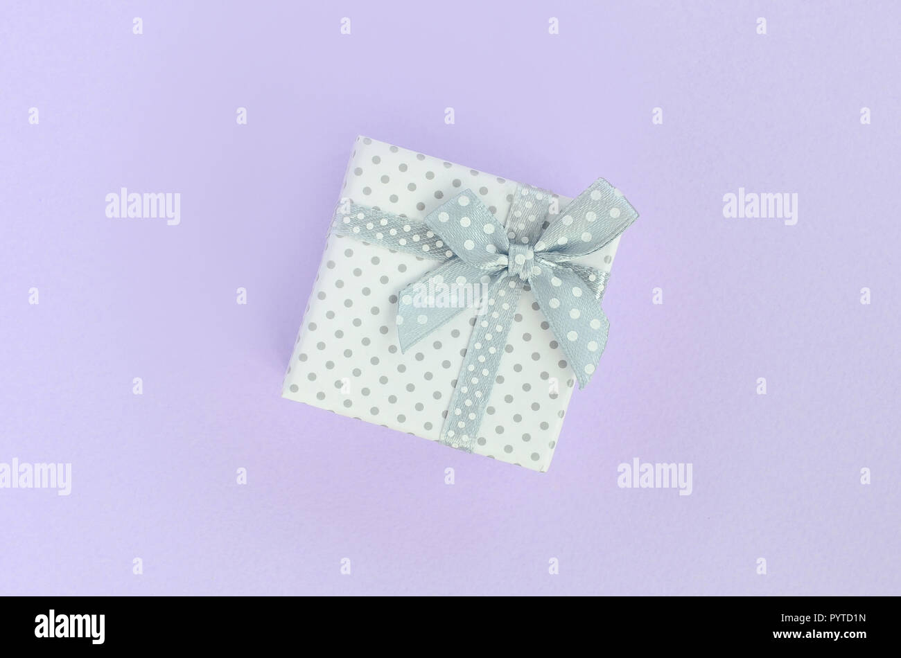 Small white gift box with ribbon lies on a violet background ...