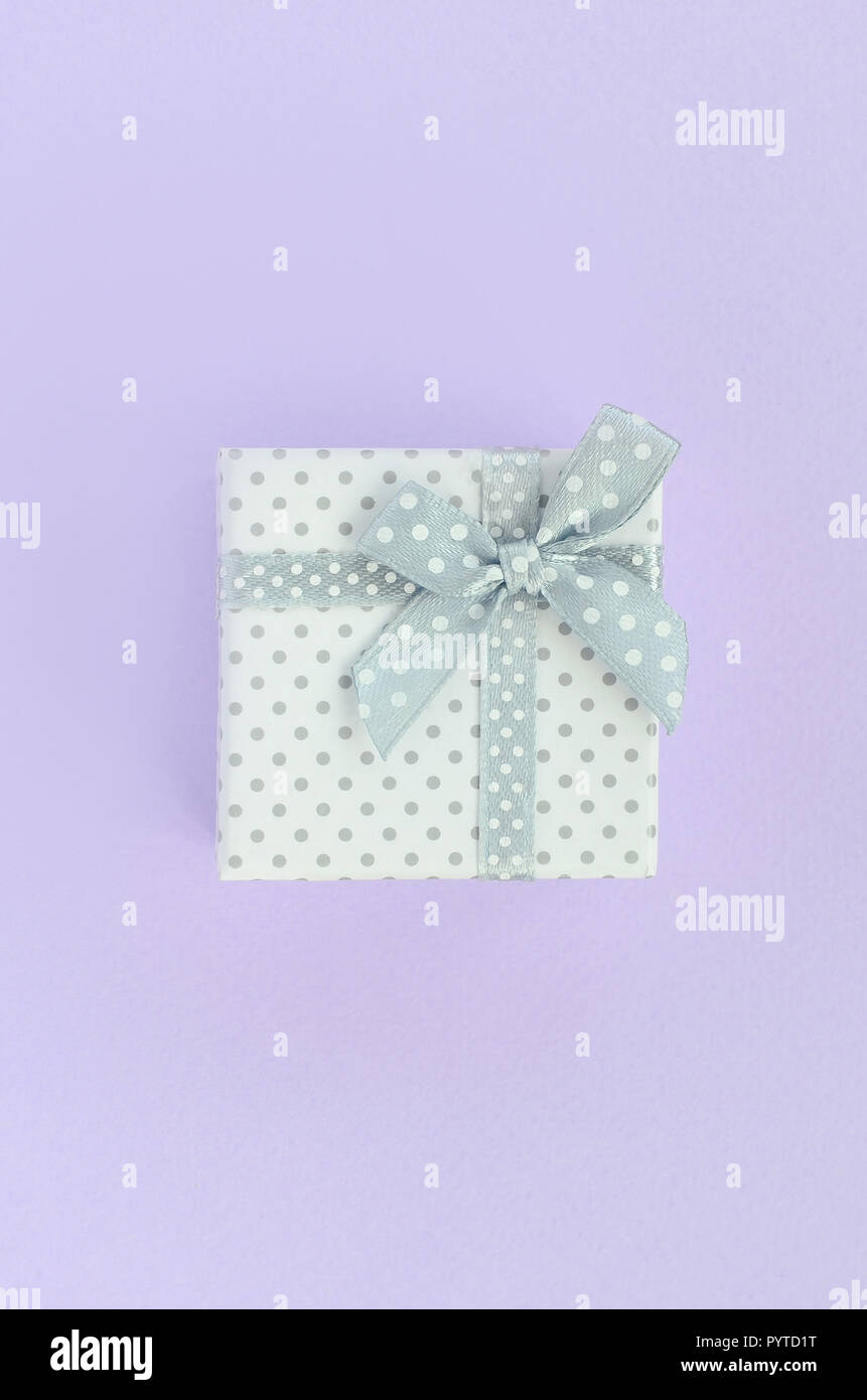 Small white gift box with ribbon lies on a violet background ...