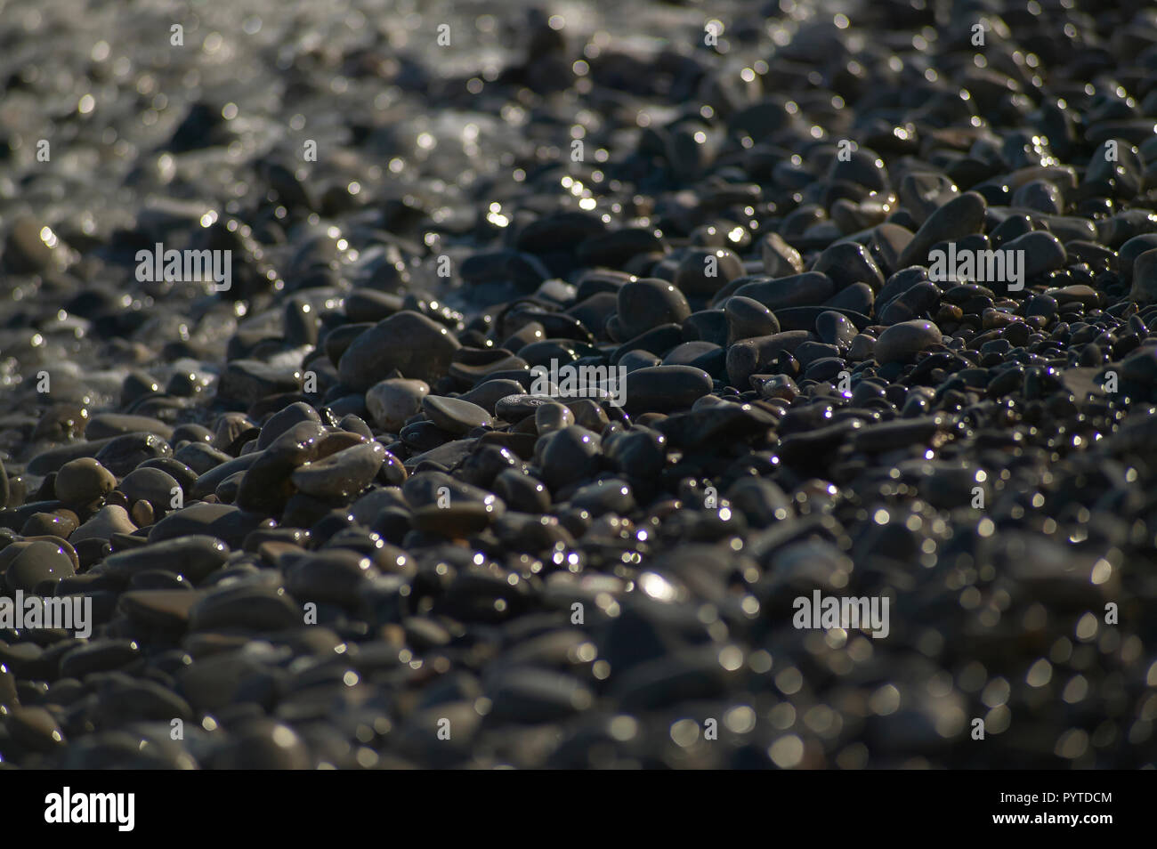 A small detail of the pebbles on a beach hit by the sea waves crashing ...