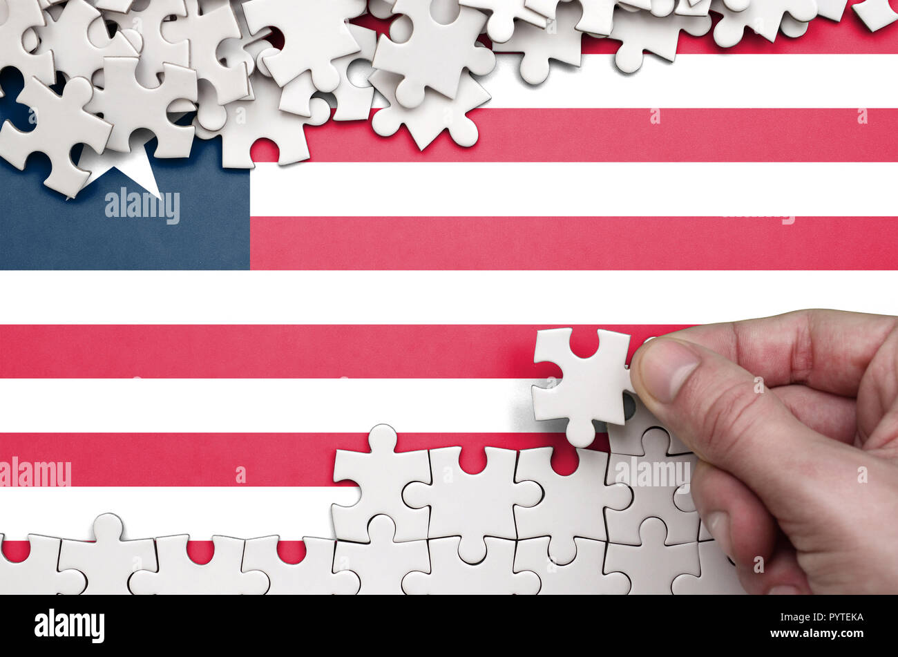 Liberia flag is depicted on a table on which the human hand folds a ...