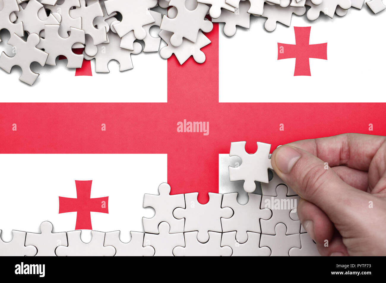 Georgia flag is depicted on a table on which the human hand folds a ...