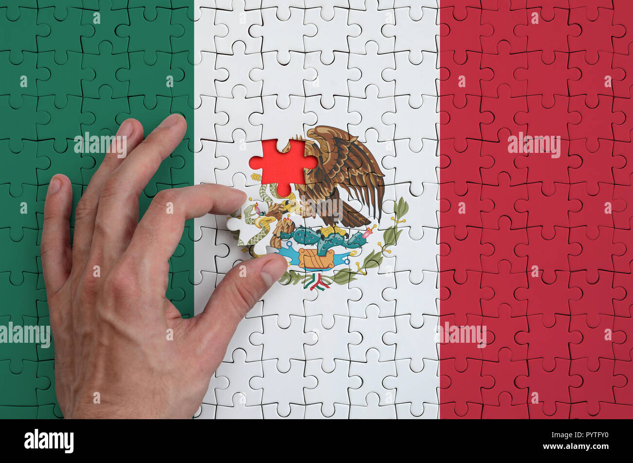 Mexico flag is depicted on a puzzle, which the man's hand completes to ...