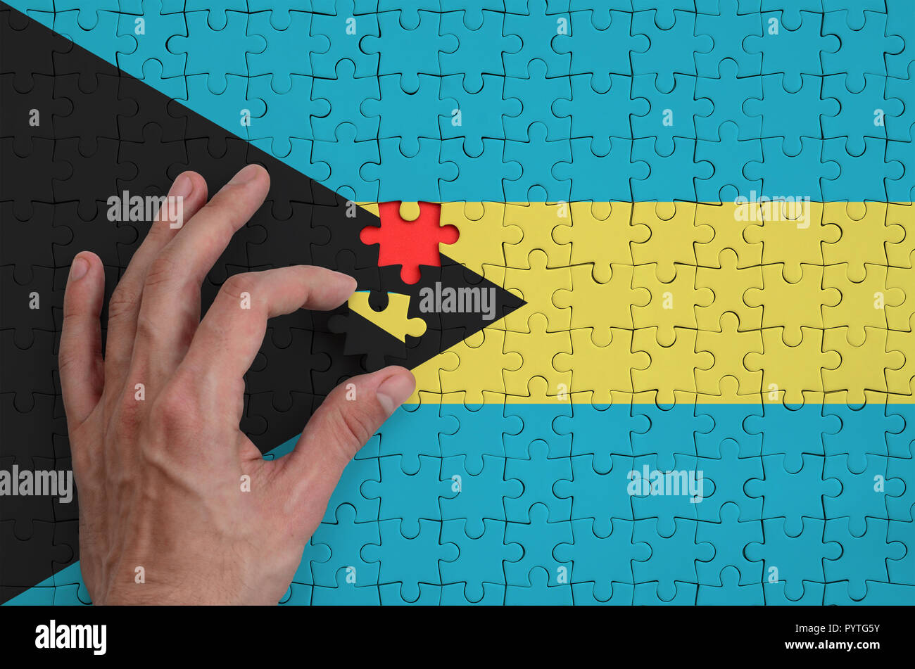 Bahamas flag is depicted on a puzzle, which the man's hand completes to ...