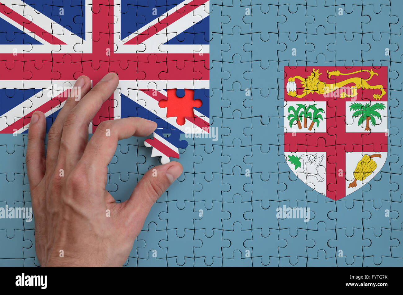 Fiji flag is depicted on a puzzle, which the man's hand completes to ...