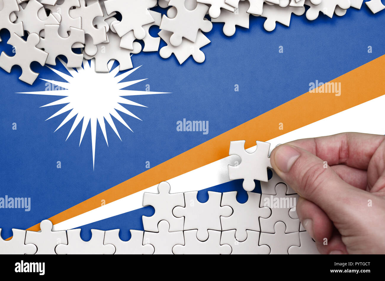 Marshall Islands flag is depicted on a table on which the human hand ...
