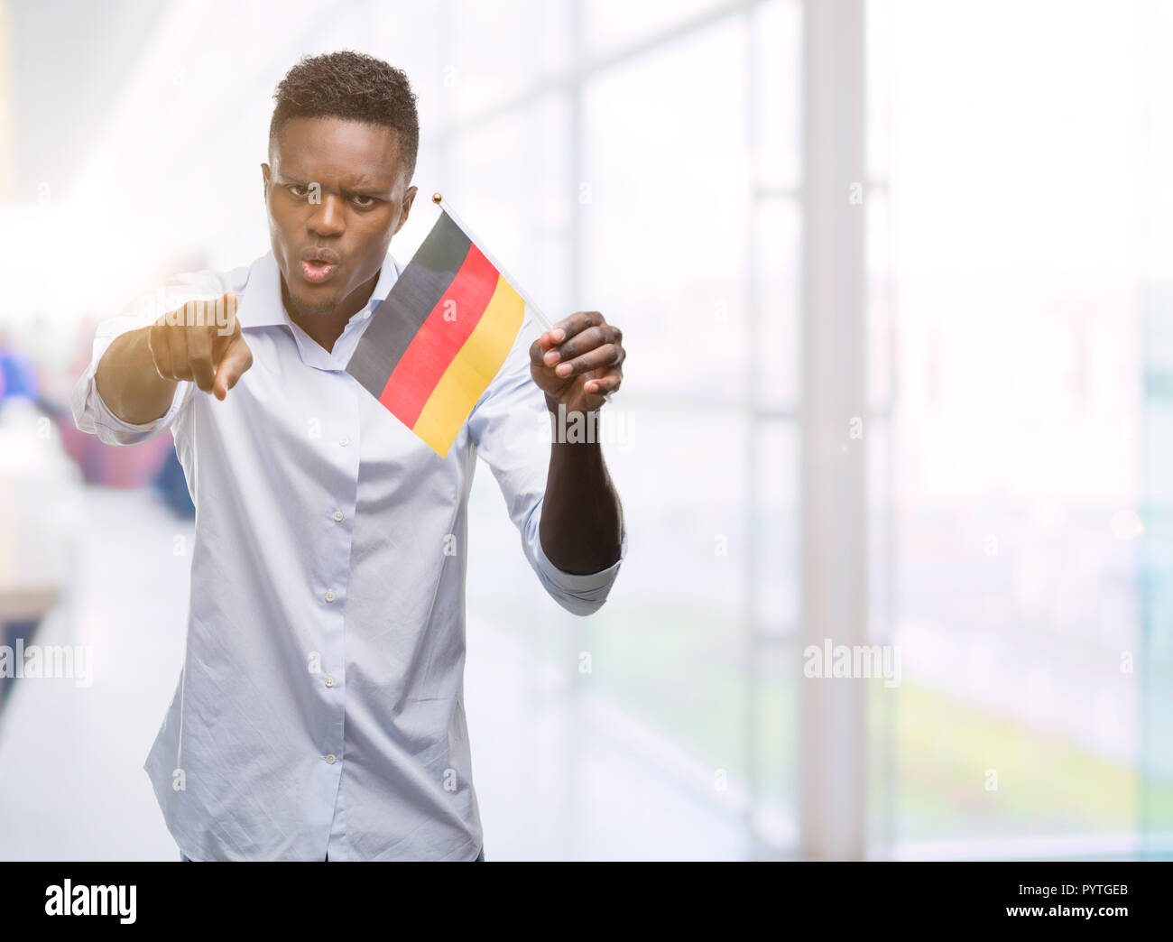 Young african american man holding german flag pointing with finger to ...