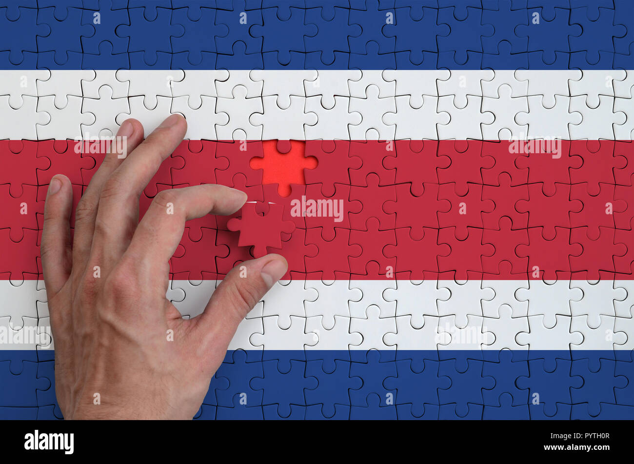 Costa Rica flag is depicted on a puzzle, which the man's hand completes ...