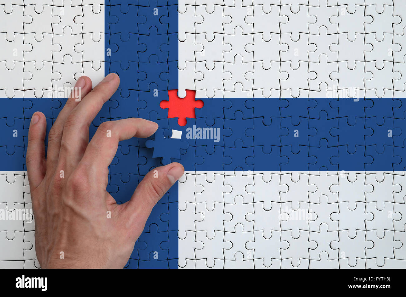 Finland flag is depicted on a puzzle, which the man's hand completes to ...