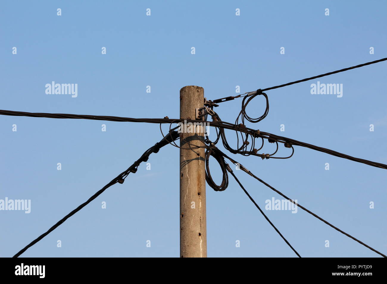 Concrete utility pole with multiple black electrical wires connected ...