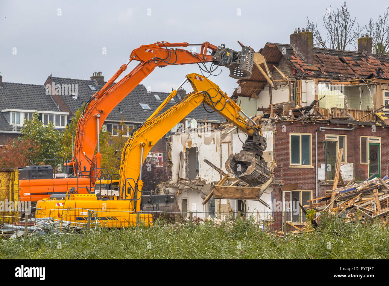 Two Demolition cranes demolishing old row of houses in the Netherlands ...