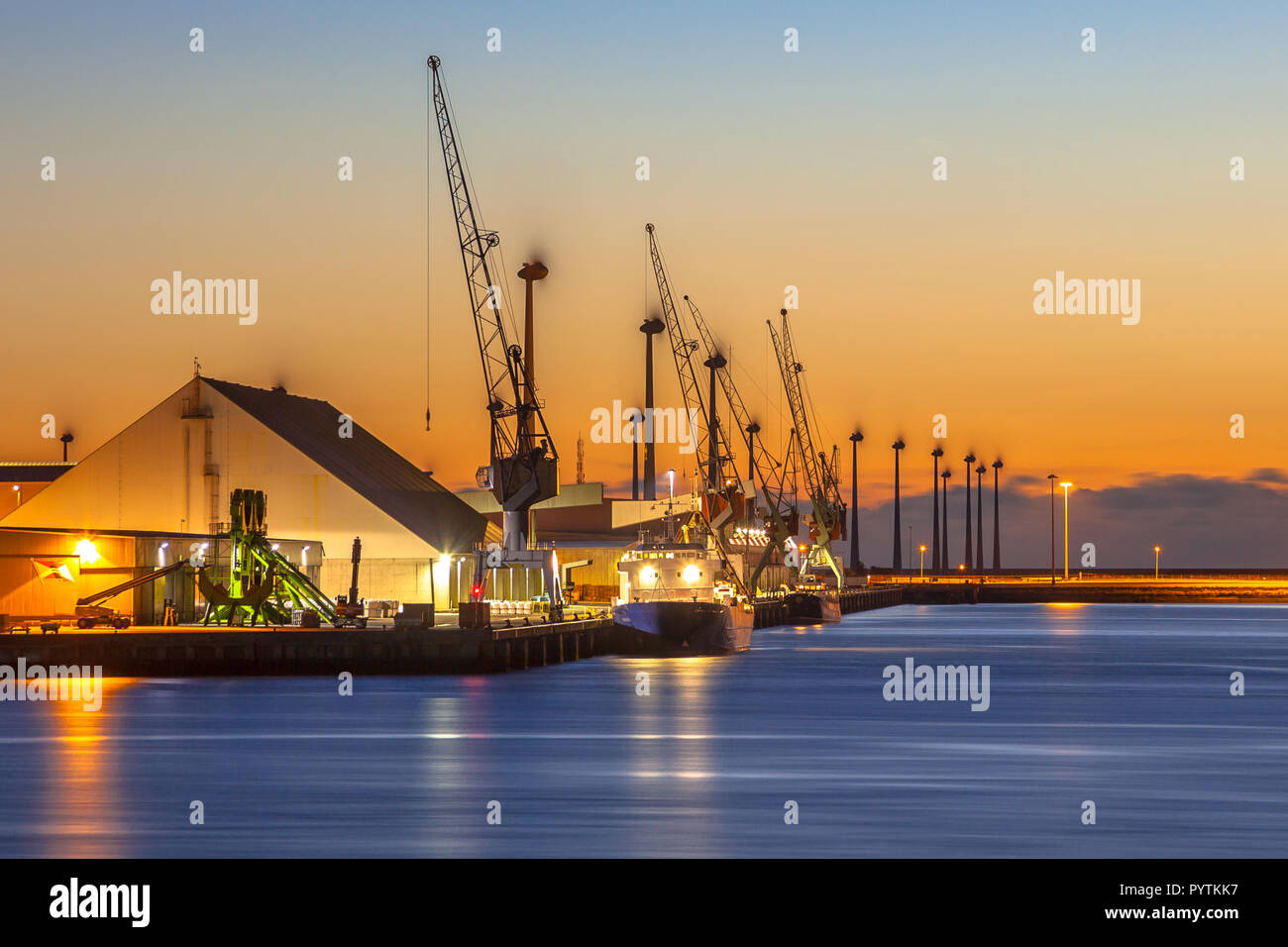 Boats on a quay in a small industrial harbor during under a colorfull ...