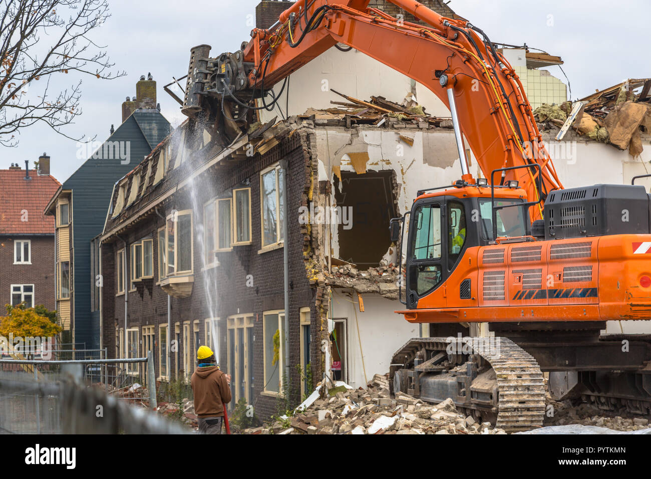 Orange Demolition crane demolishing old row of houses in the ...