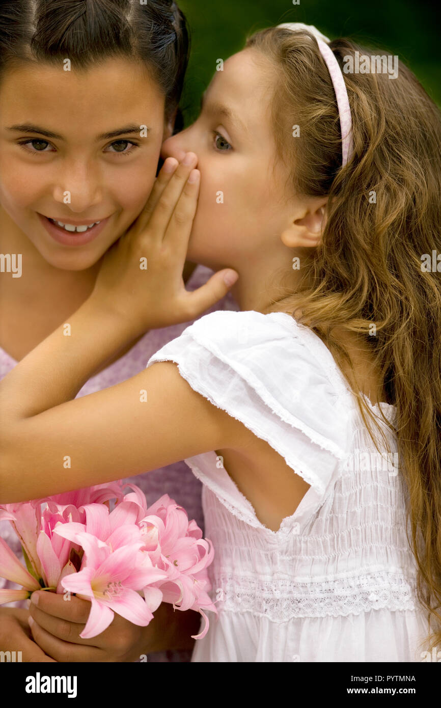 Young girl whispers in her sisters ear Stock Photo - Alamy