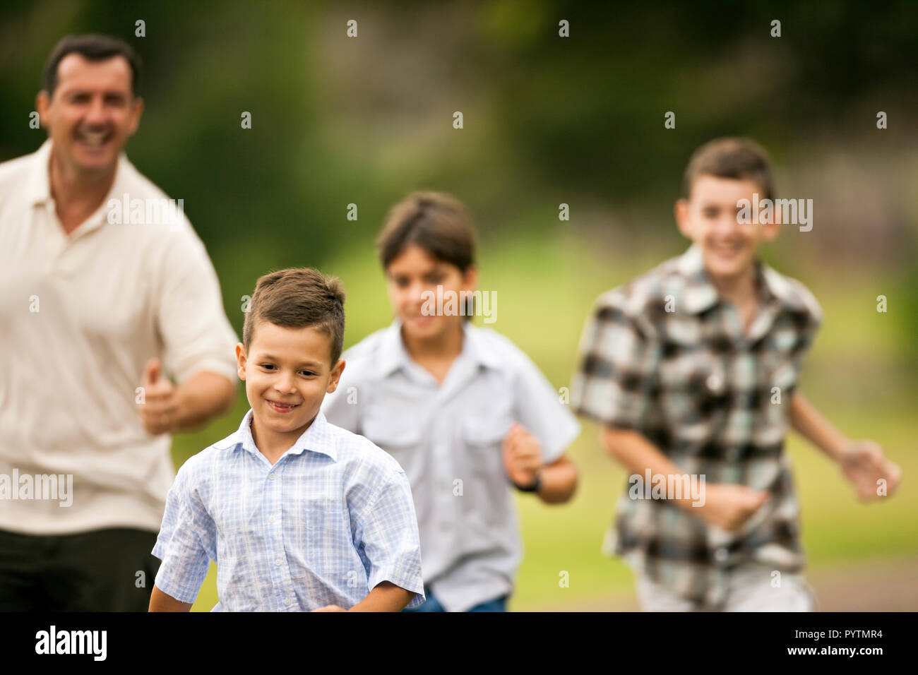 Three boys running with their father Stock Photo - Alamy