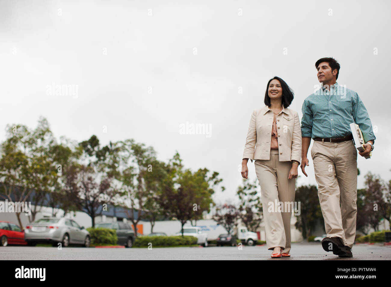 Smiling colleagues walking and talking together Stock Photo - Alamy