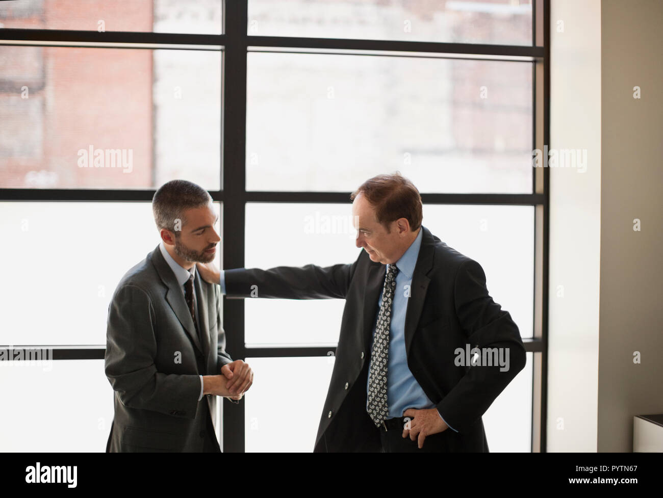 Two businessmen talk, one has hand on the others shoulder Stock Photo ...