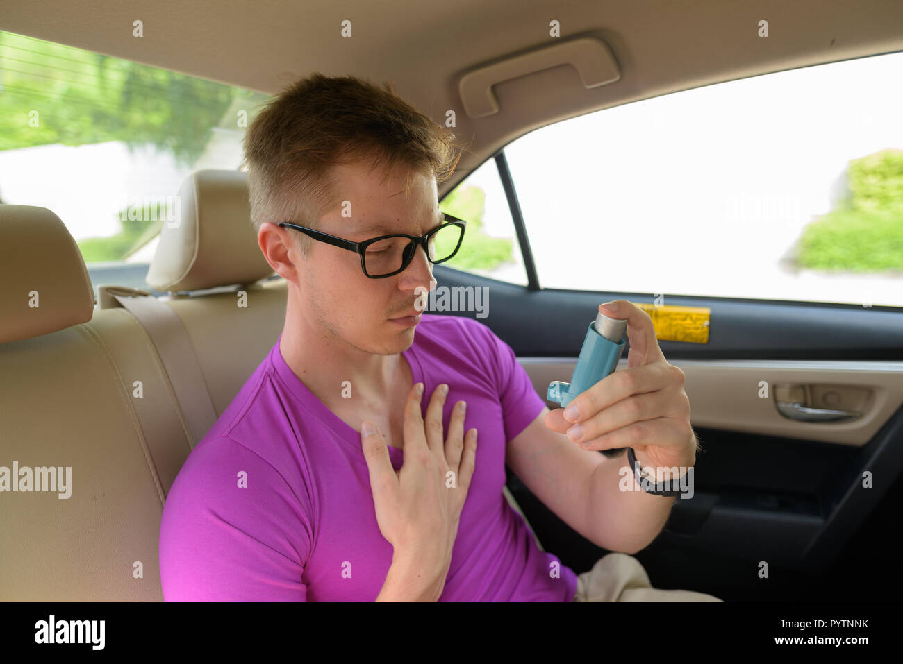 Man using asthma inhaler in back seat of car Stock Photo - Alamy