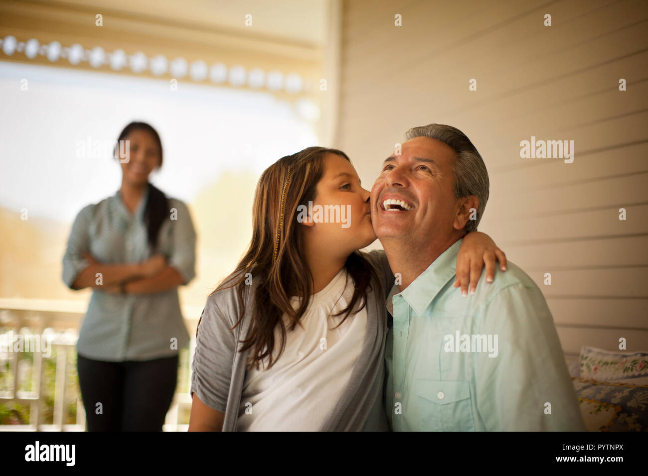 Girl kissing her happy father on the porch Stock Photo - Alamy